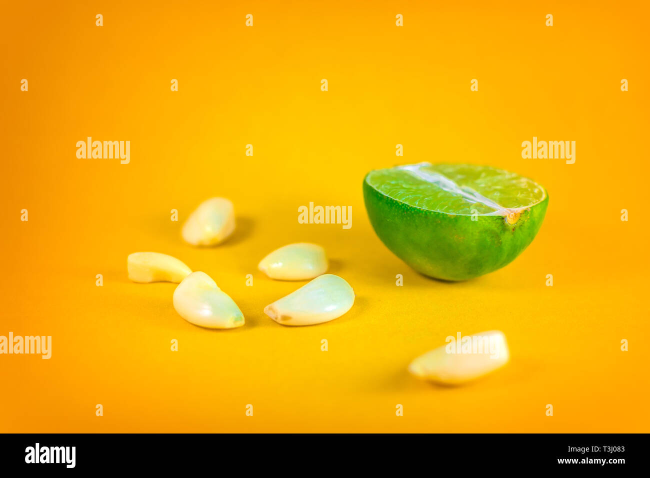 Graphic close up of a slice of lemon surrounded by garlic cloves over a ...