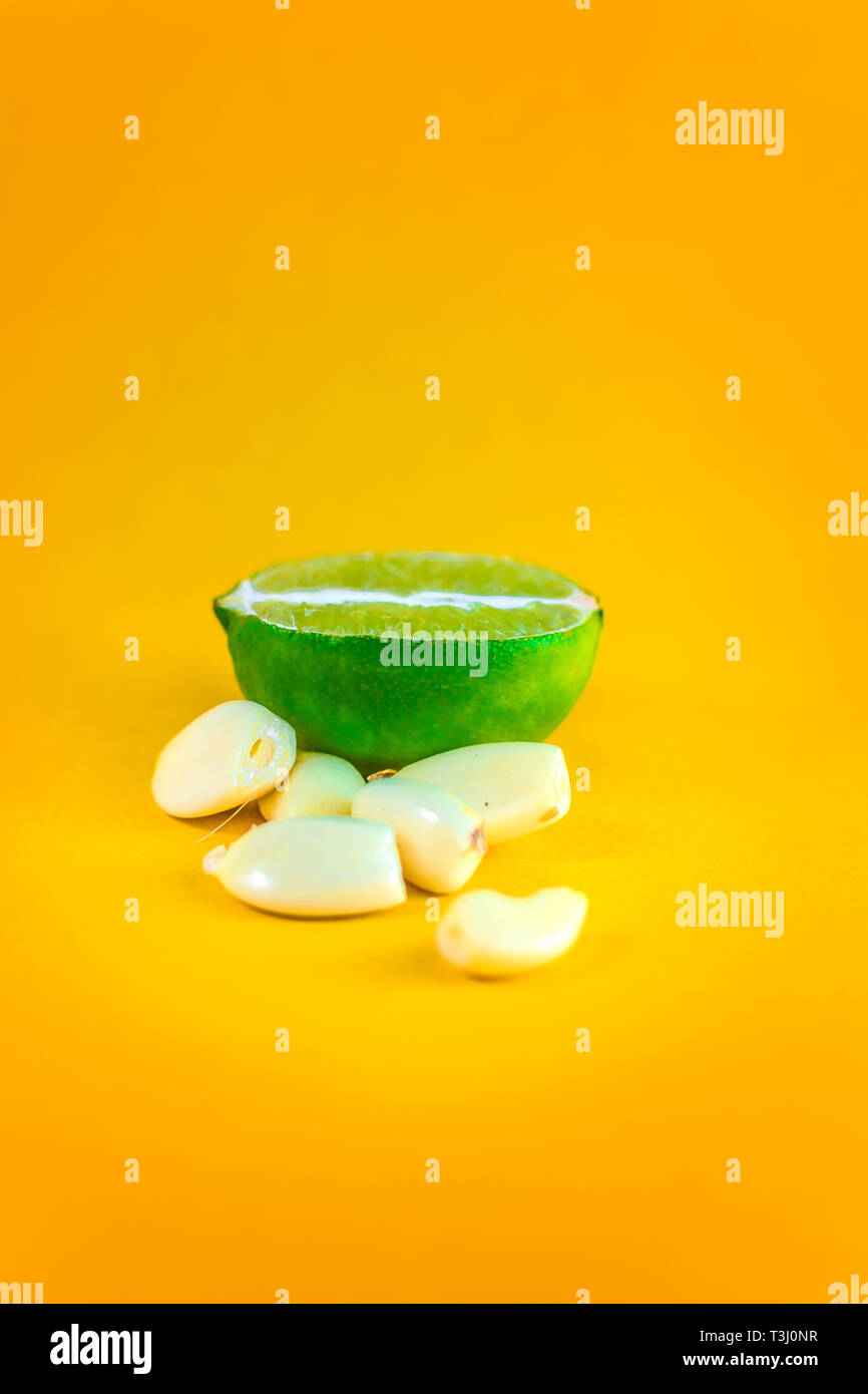 Graphic close up of a slice of lemon surrounded by garlic cloves over a ...
