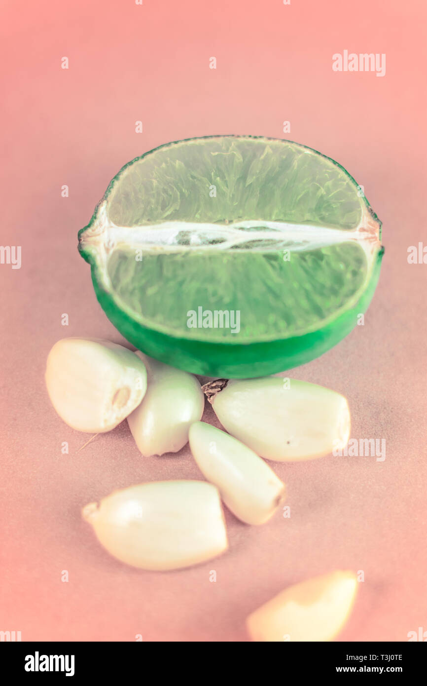 Top close up of a slice of lemon surrounded by garlic cloves over a ...