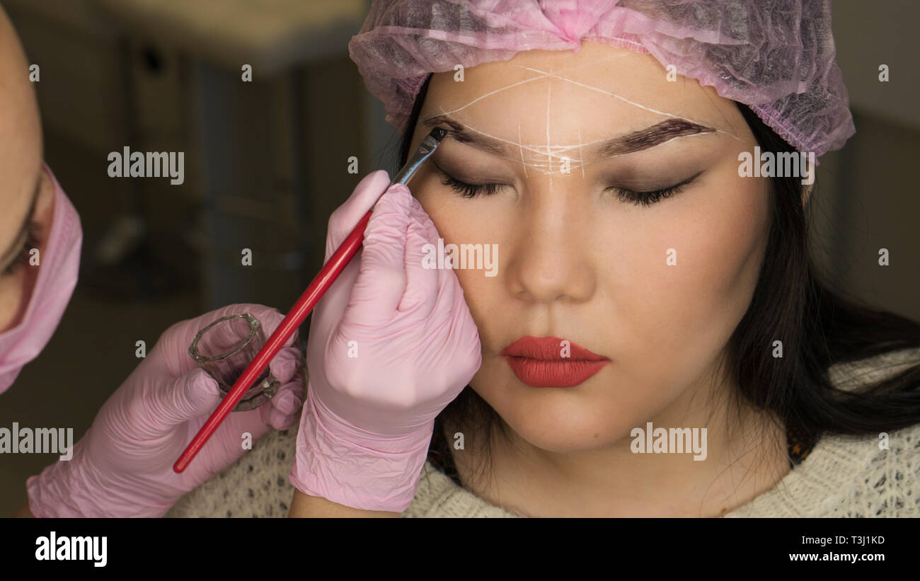 Microbleeding and eyebrow architecture. Beautician applies coloring ...