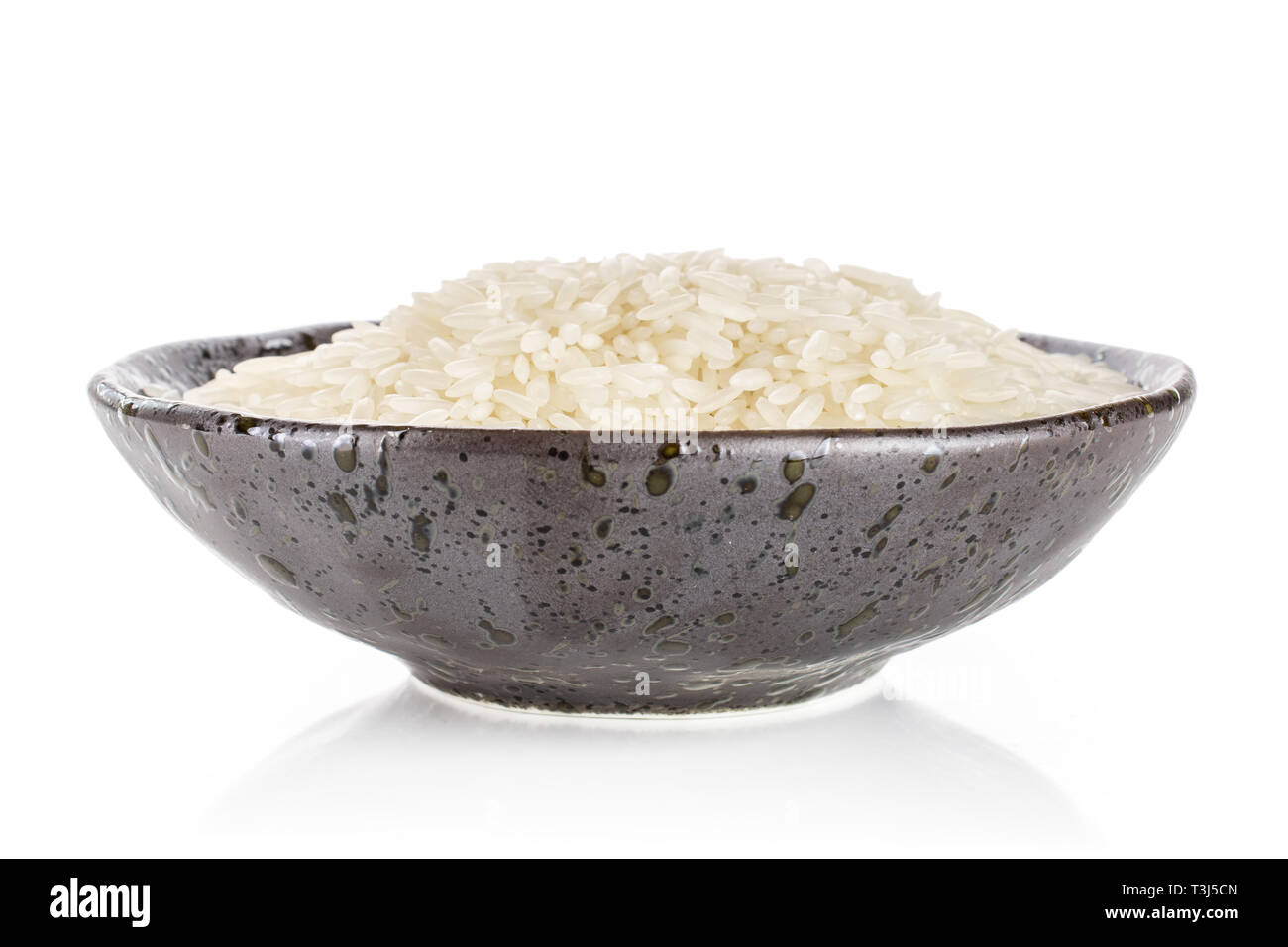 Lot of whole white jasmine rice grains on grey ceramic plate isolated ...