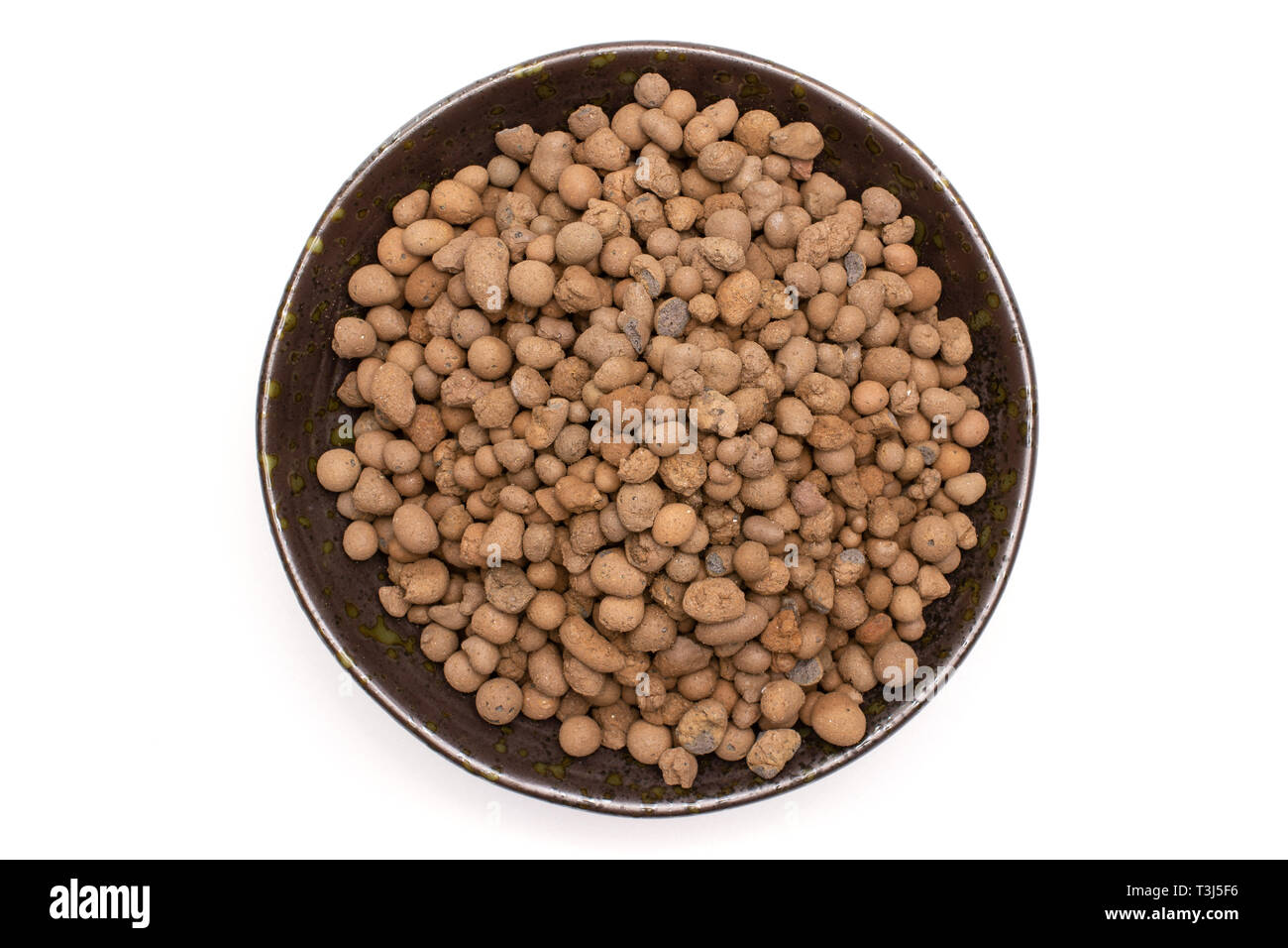 Lot of whole brown clay pebbles (leca) on grey ceramic plate flatlay ...