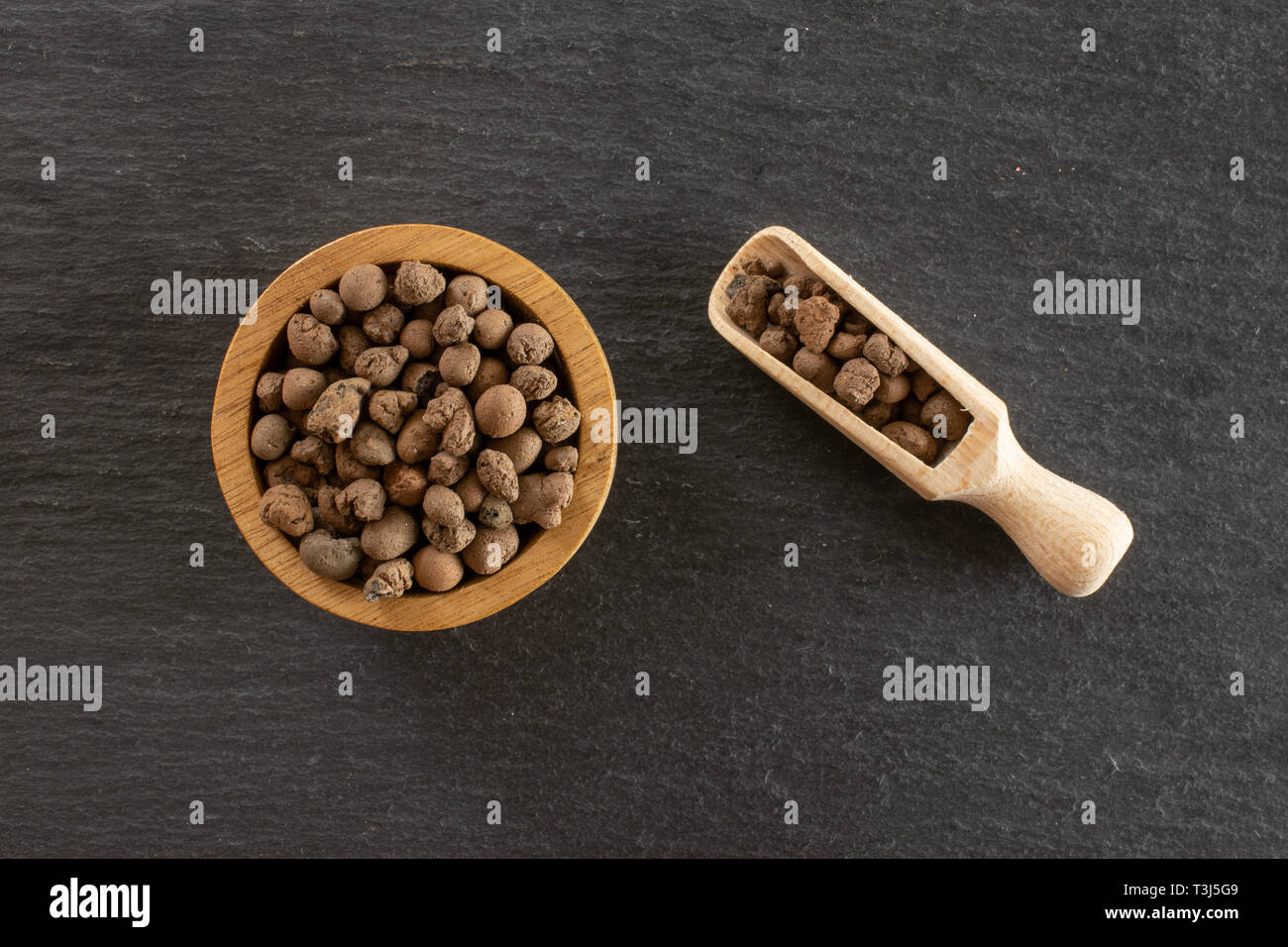 Lot of whole brown clay pebbles (leca) with wooden bowl and wooden ...