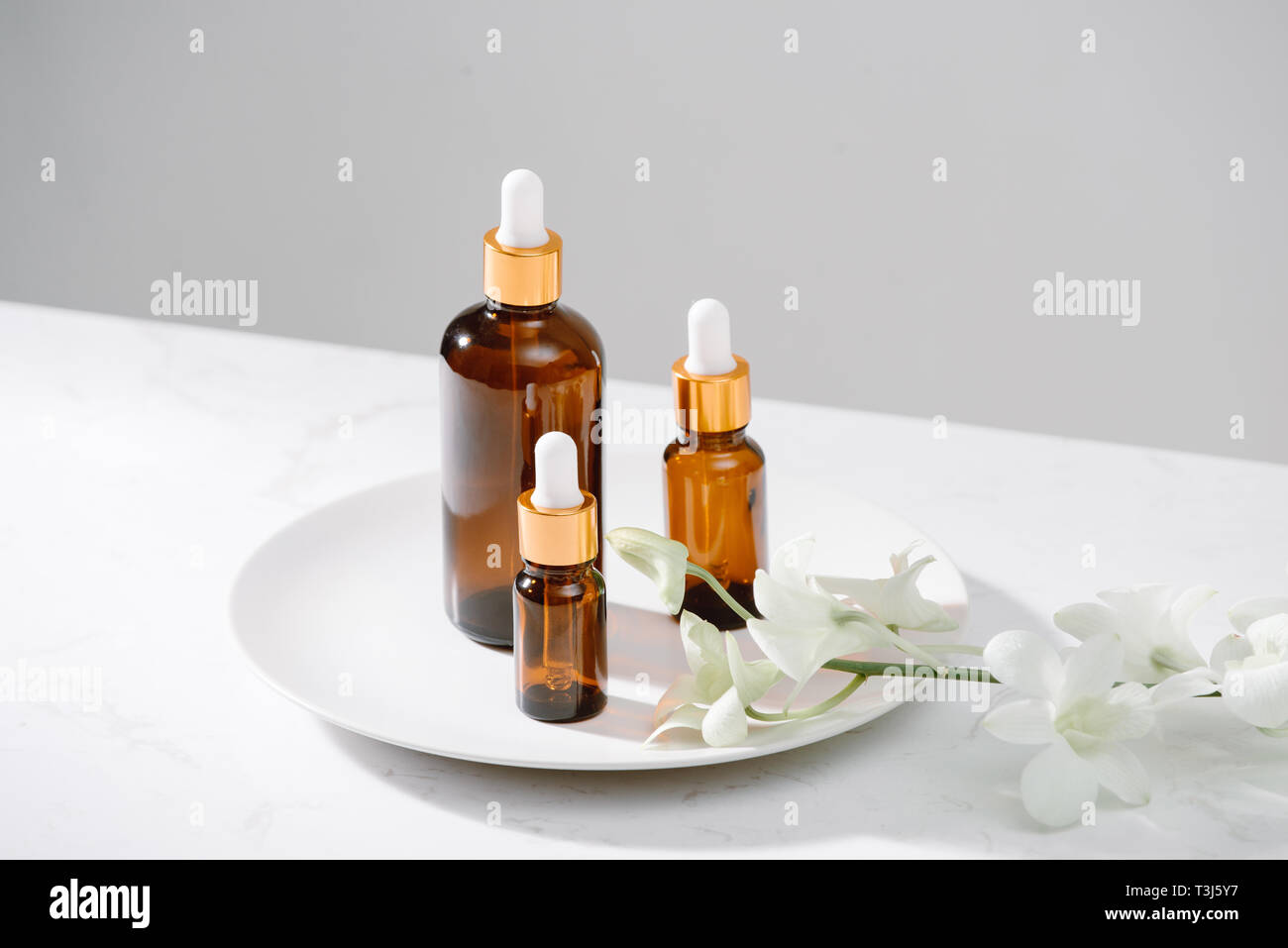Spa setting with orchids and essential oil in a glass bottle ...