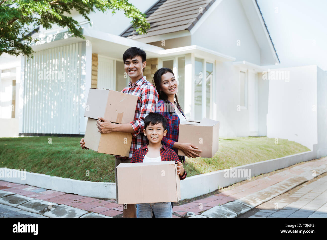 family with kid standing in front of their house Stock Photo - Alamy