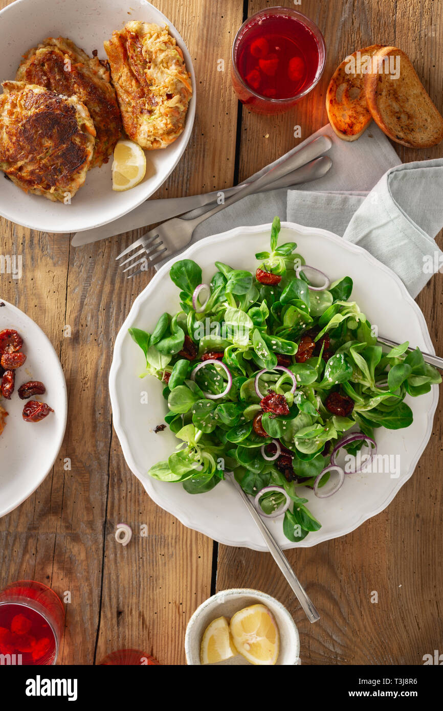 Vegetarian dinner table with bowl of green salad and vegetable cutlets ...