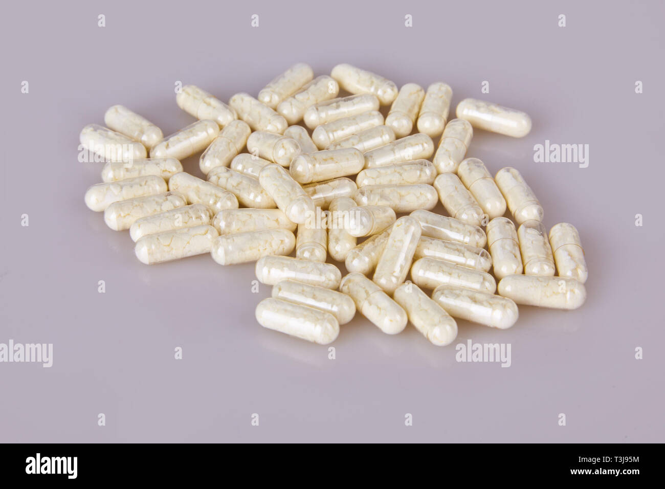 Spilled capsules on the white background. Vitamin supplements tablets ...