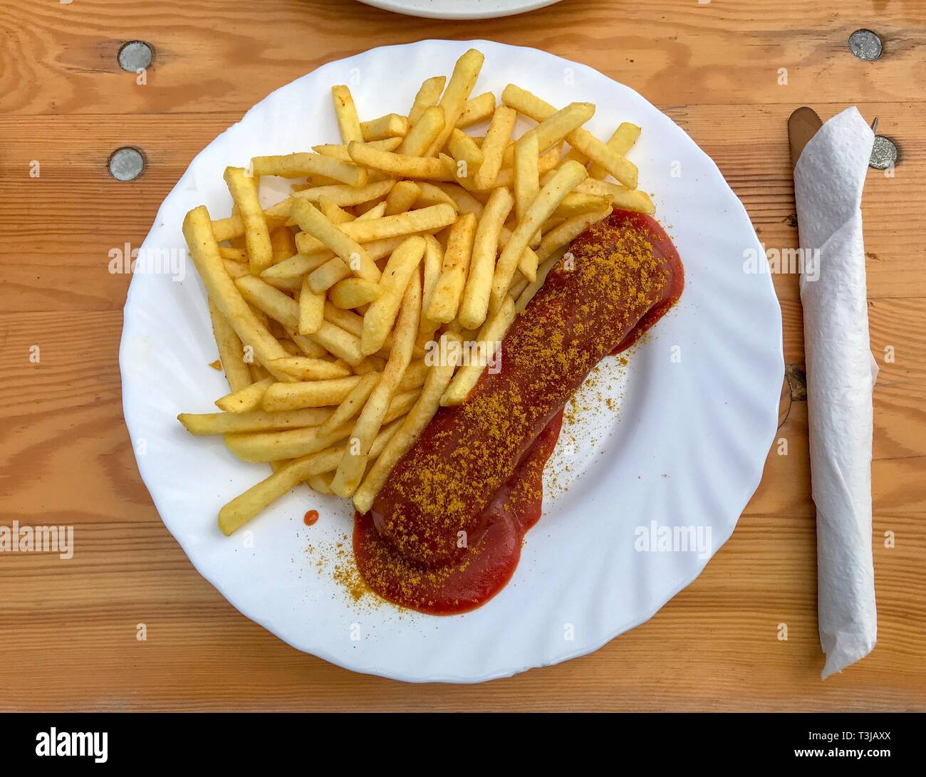 Original Berlin curry sausage, French fries, cutlery, napkin, wooden ...