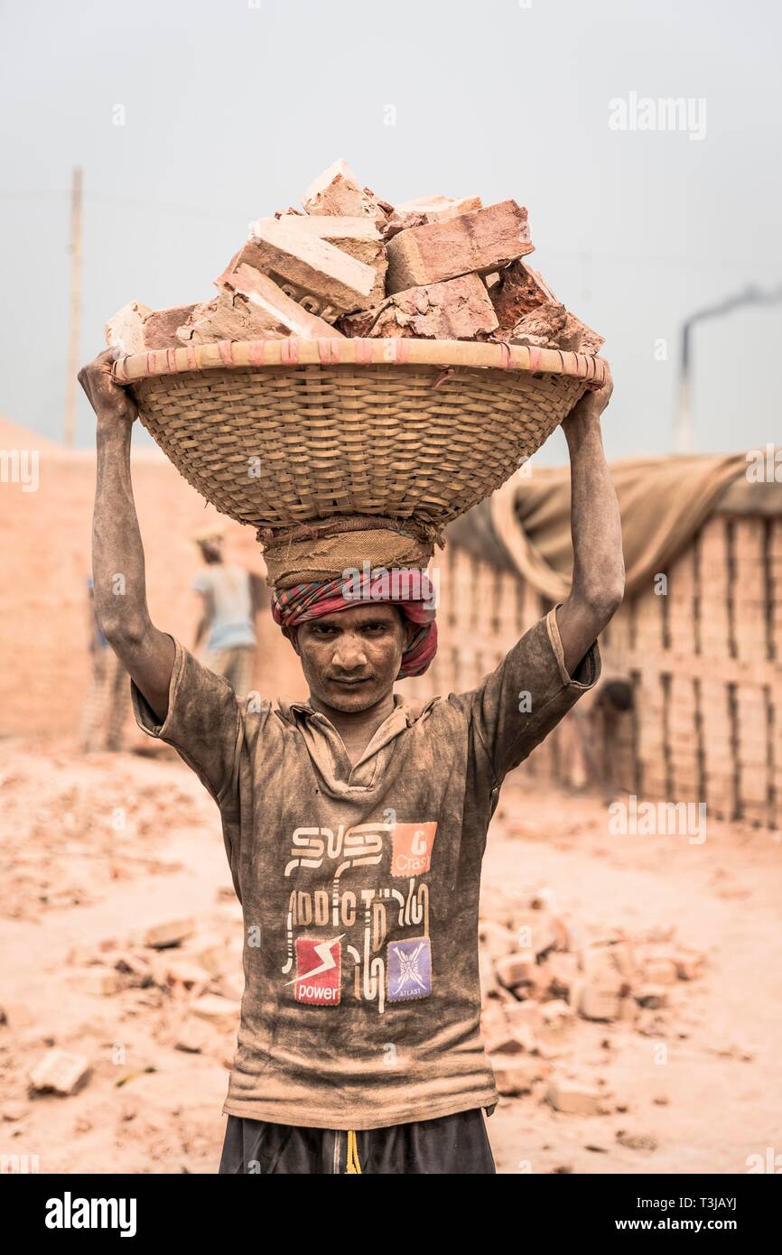Brickyard worker carrying bricks in a basket on his head, Dhaka ...