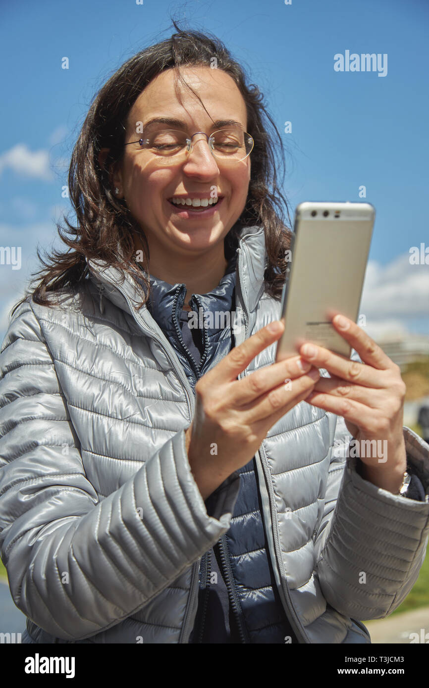 Pretty hispanic woman with mobile make self-portrait in a sunny day in ...