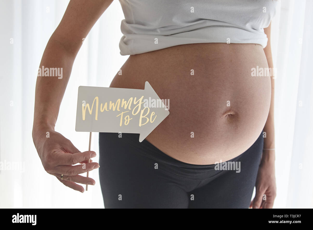 Pregnant woman holding a sign writing "mummy to be Stock Photo - Alamy