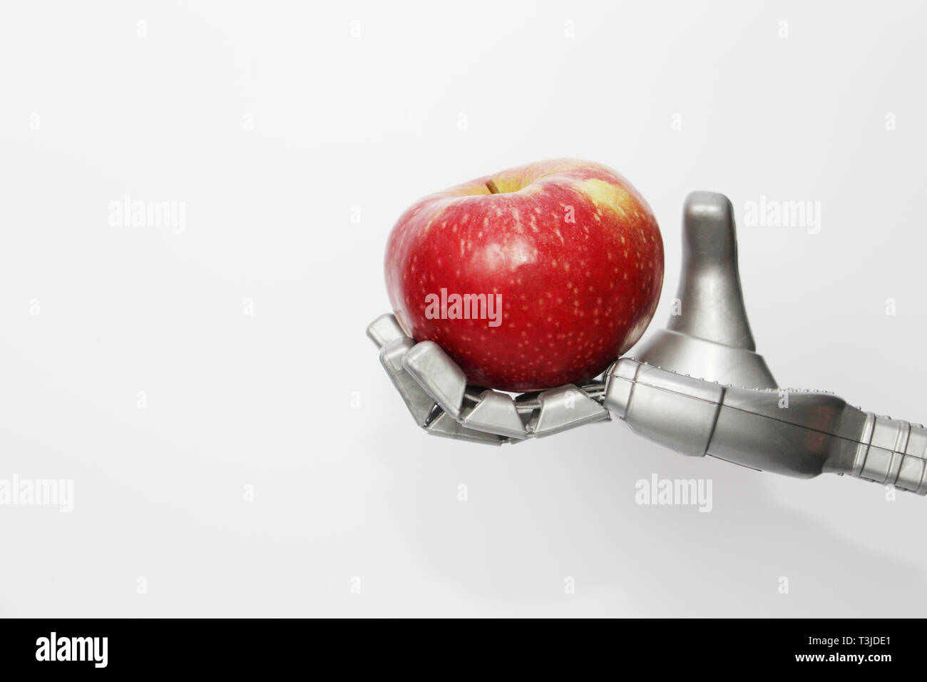 A robot hand is holding a red apple. Modern technology and robotics ...