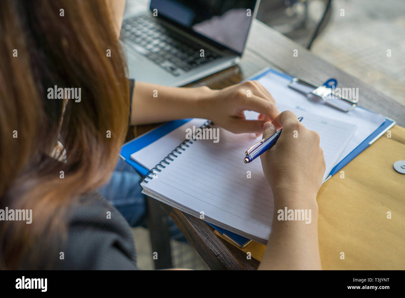 Young woman writing notes in the office Stock Photo - Alamy