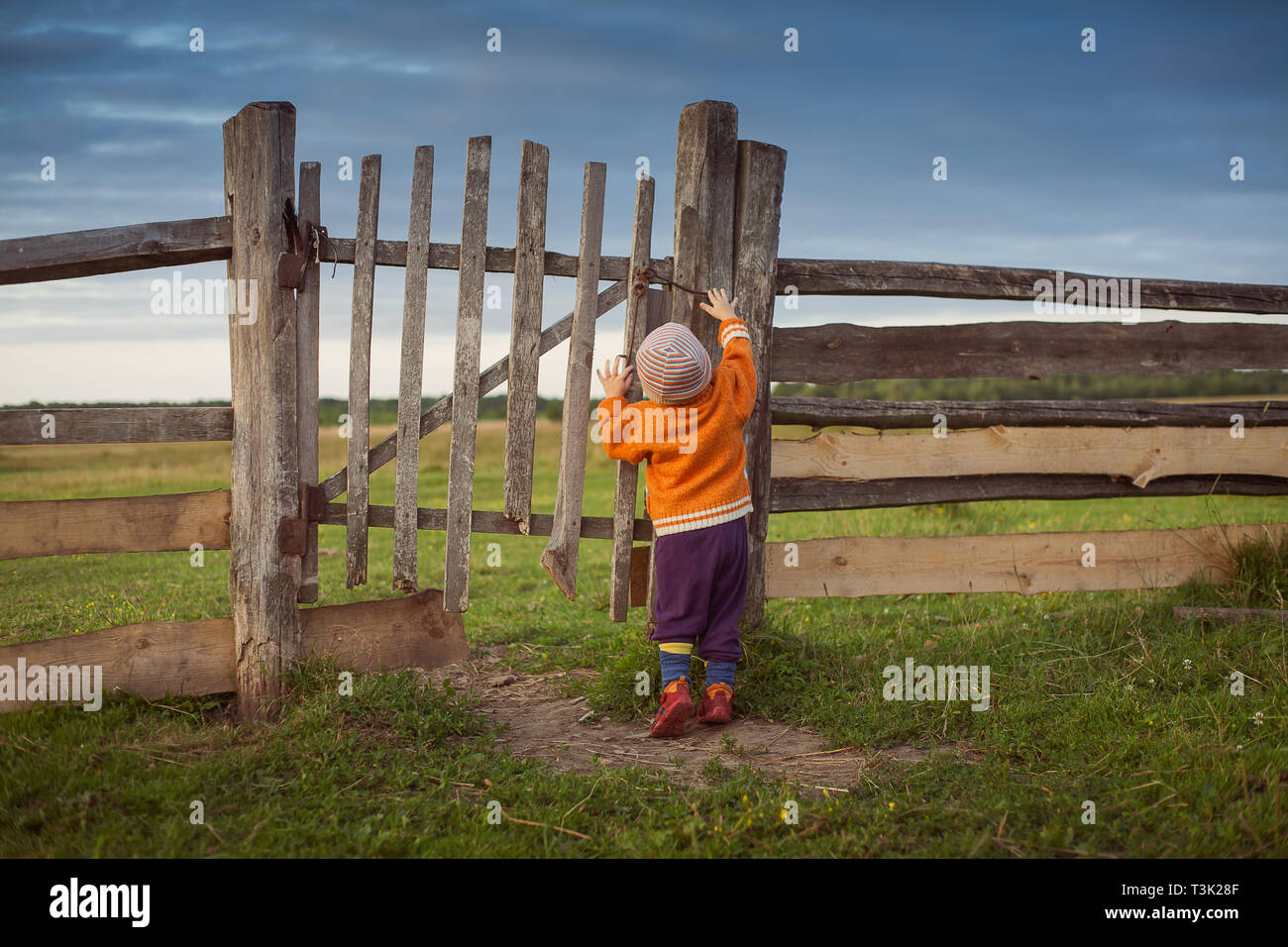 Little child opening old gates. The storm approaching Stock Photo - Alamy