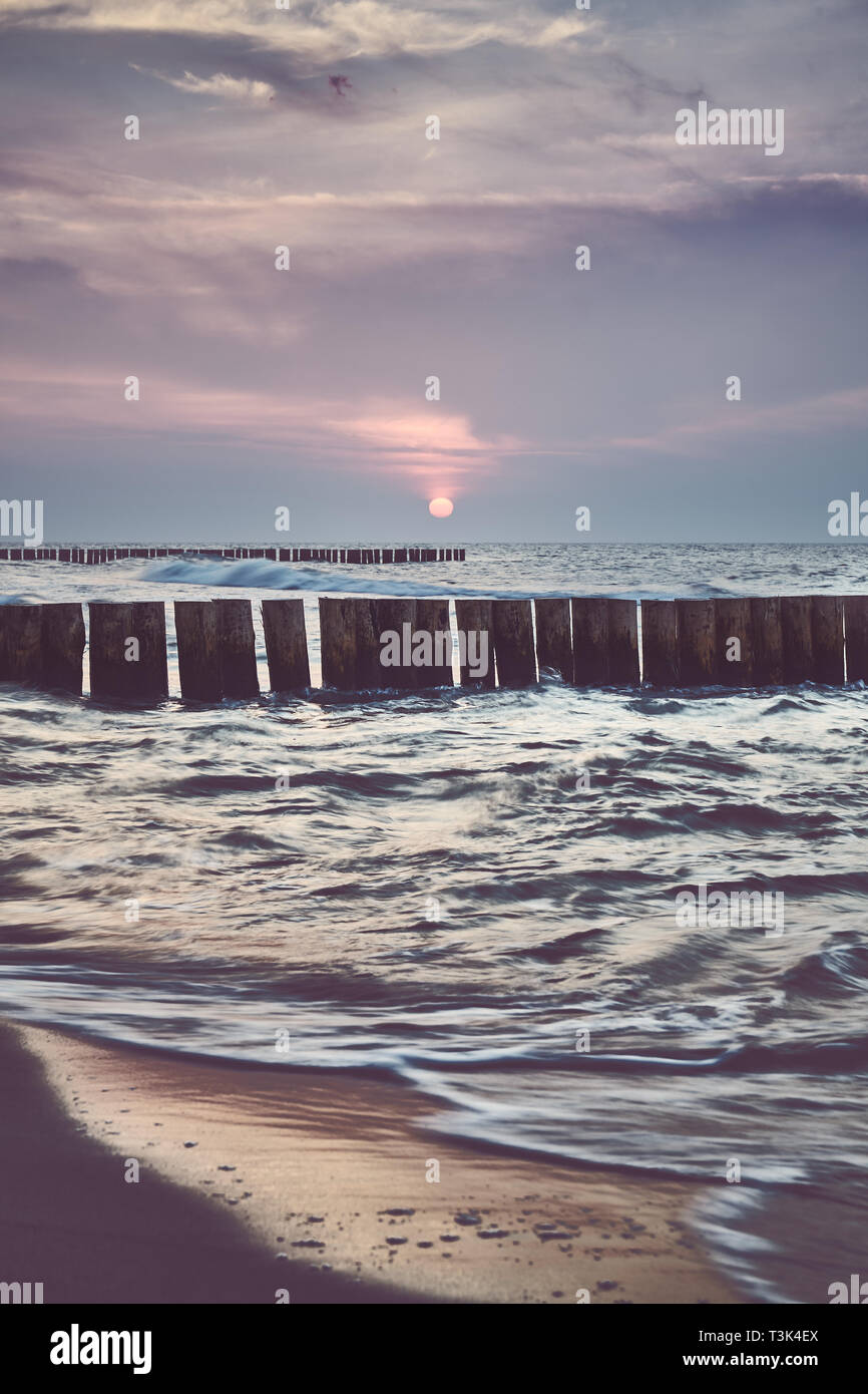Wooden sea breakwater at sunset, color toning applied, long exposure ...