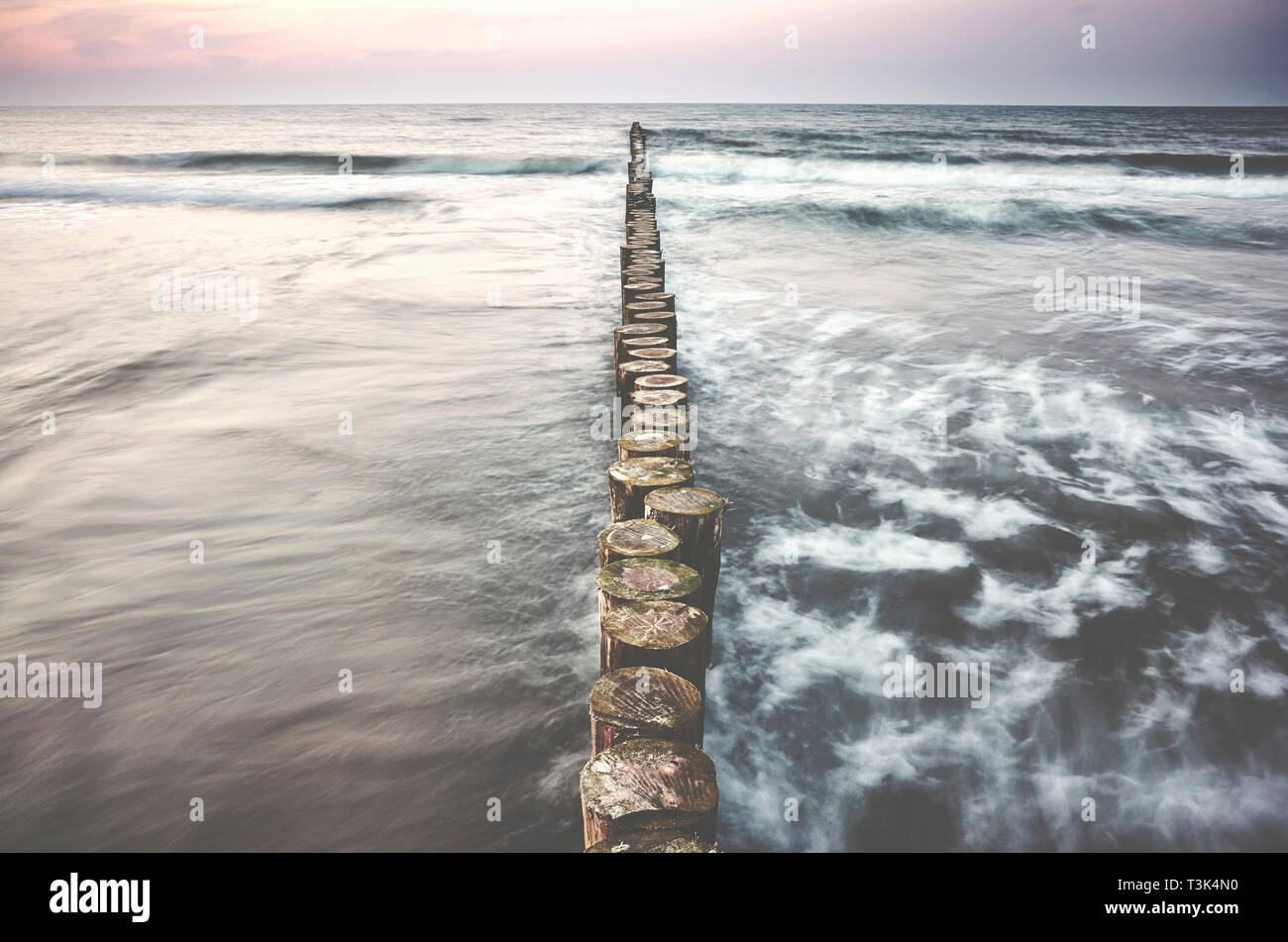 Wooden sea breakwater at sunset, color toning applied, long exposure ...