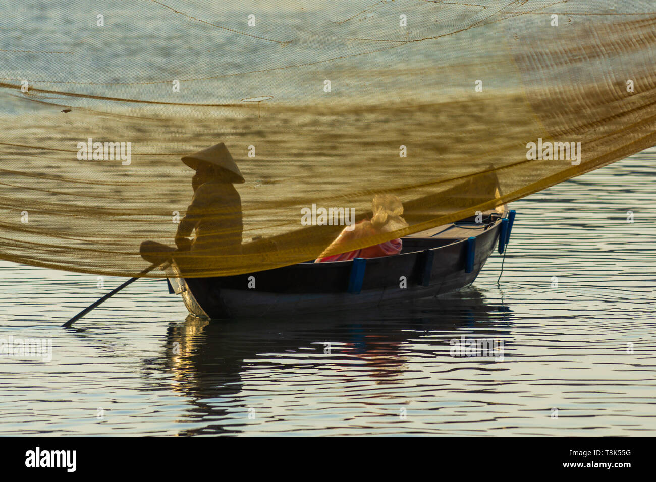 Vietnamese woman in traditional bamboo hat rowing on the Thu Bon River ...
