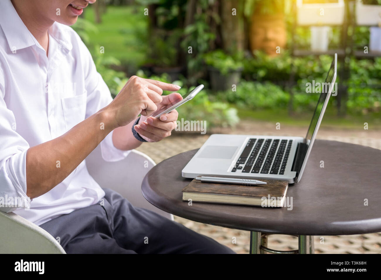 Man working on modern laptop sitting outside natural hardwood desk with ...