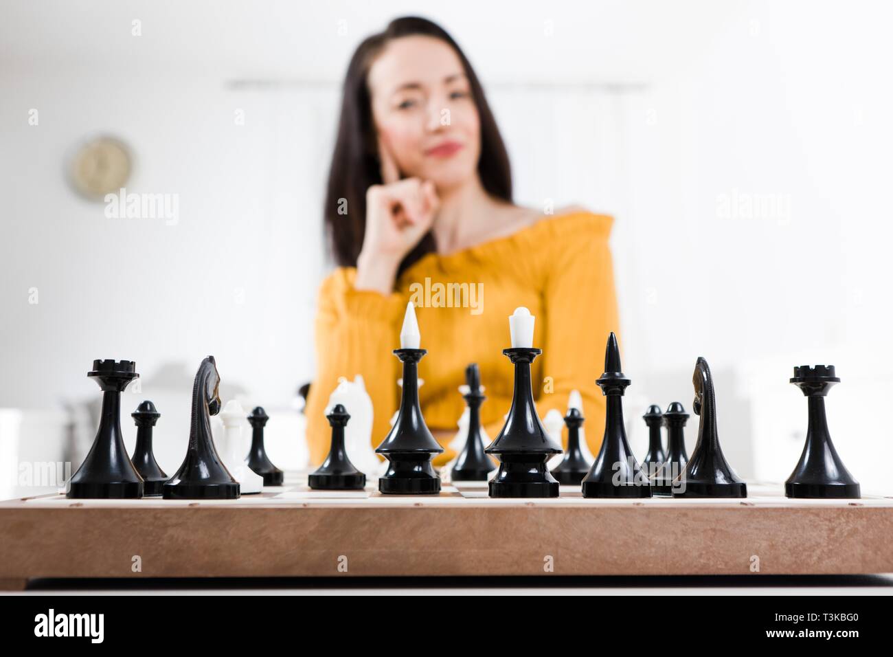Woman in yellow dress sitting in front of chess and planning strategy ...
