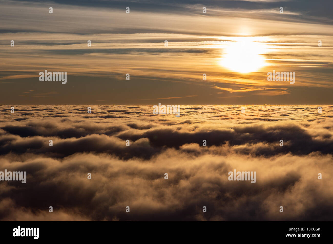 Beautiful sunset over a valley filled by fog with mountains and hills ...
