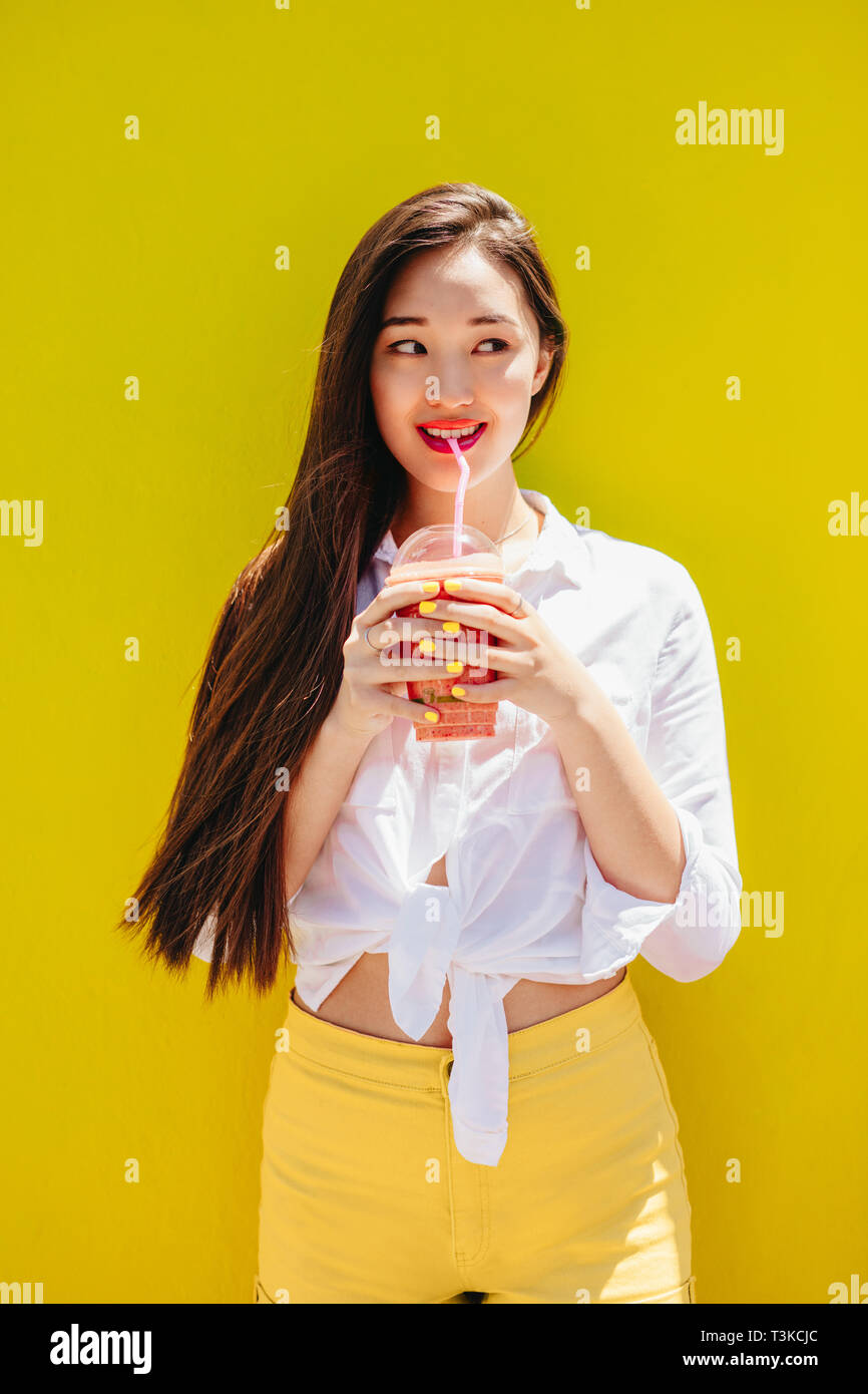 Portrait of a glamorous woman drinking juice using a straw. Smiling ...