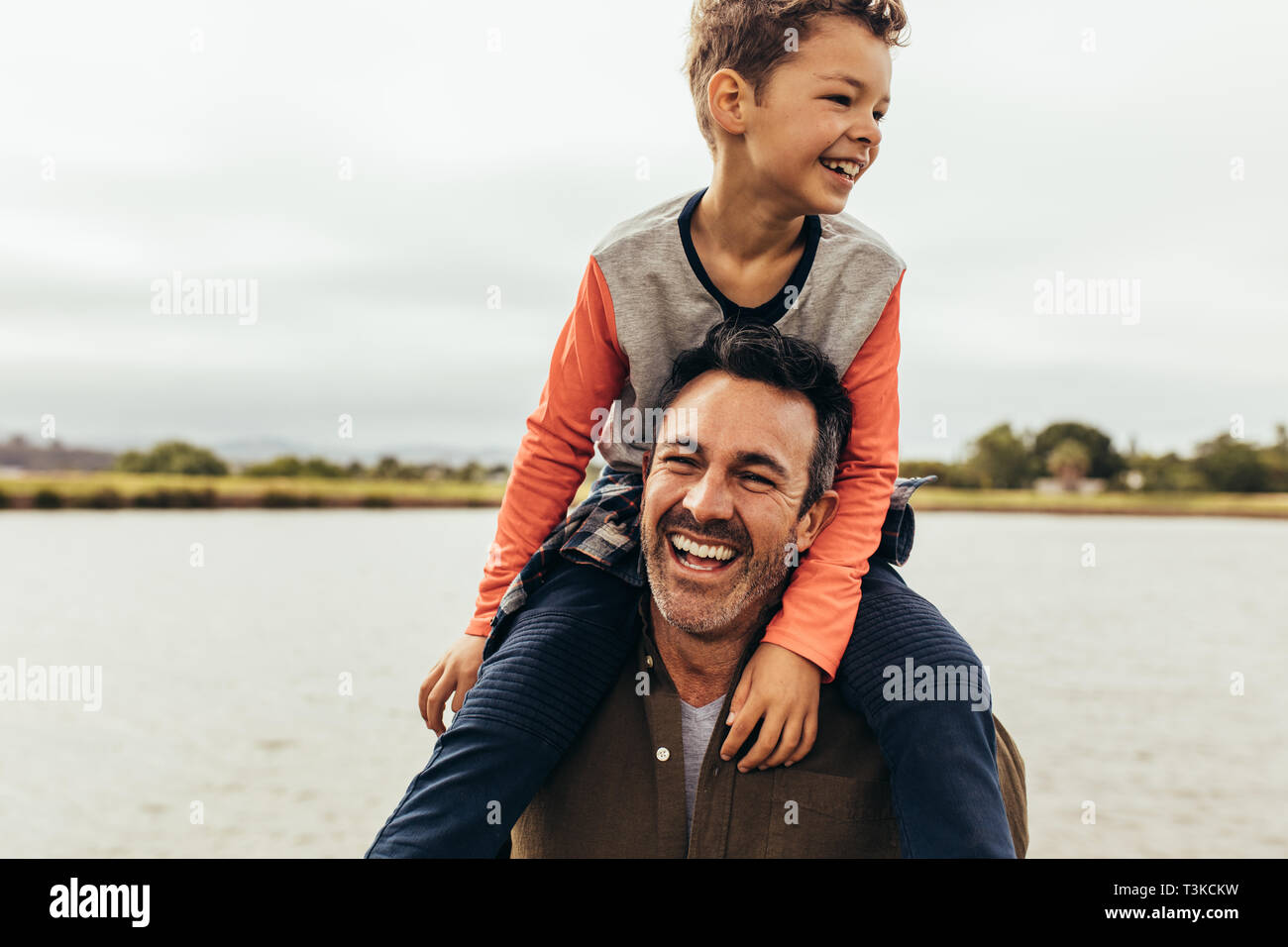 Kid sitting on the shoulders of his father and having fun. Portrait of ...
