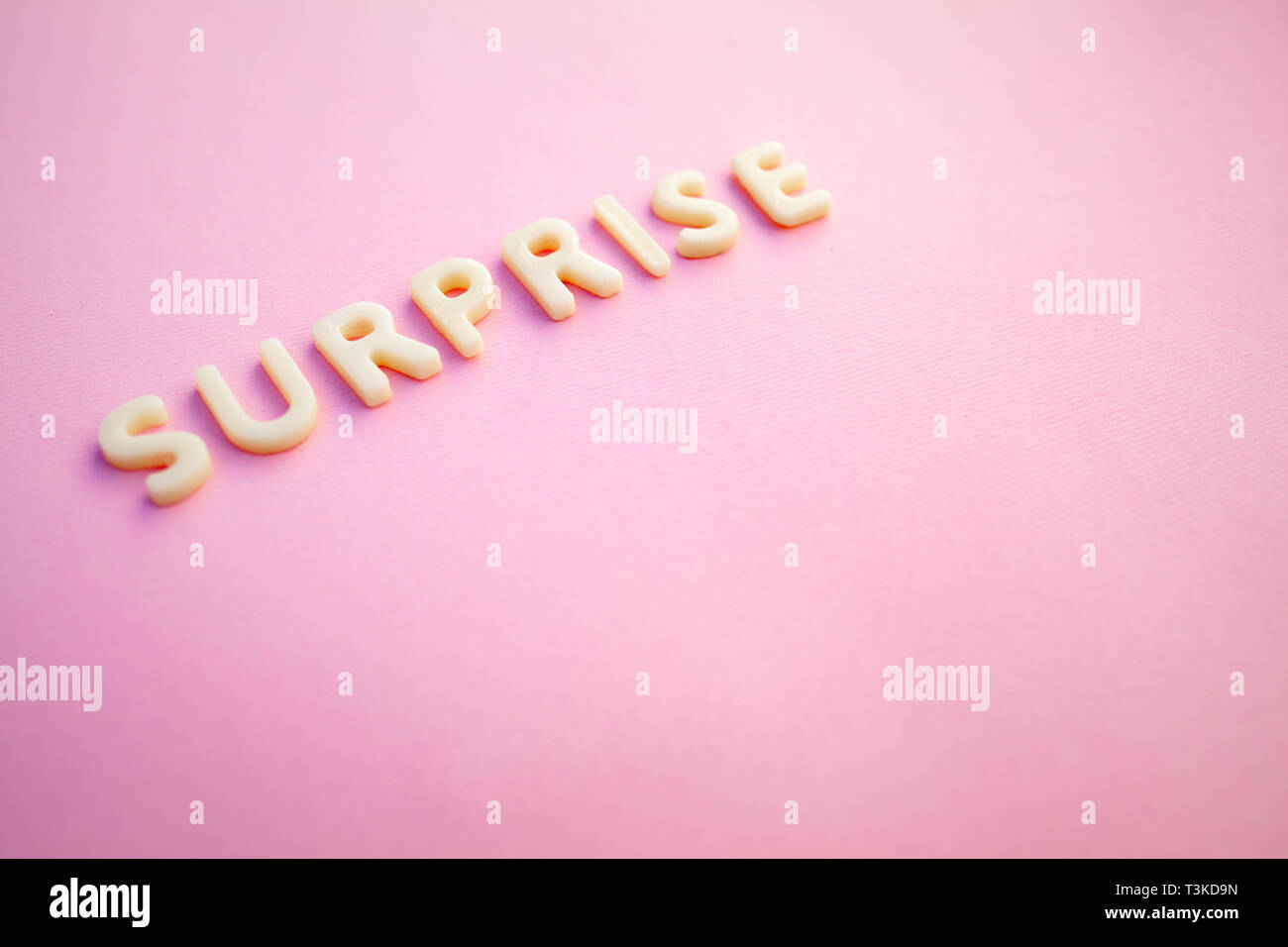 Surprise word written in voluminous white letters on a beautiful pink ...