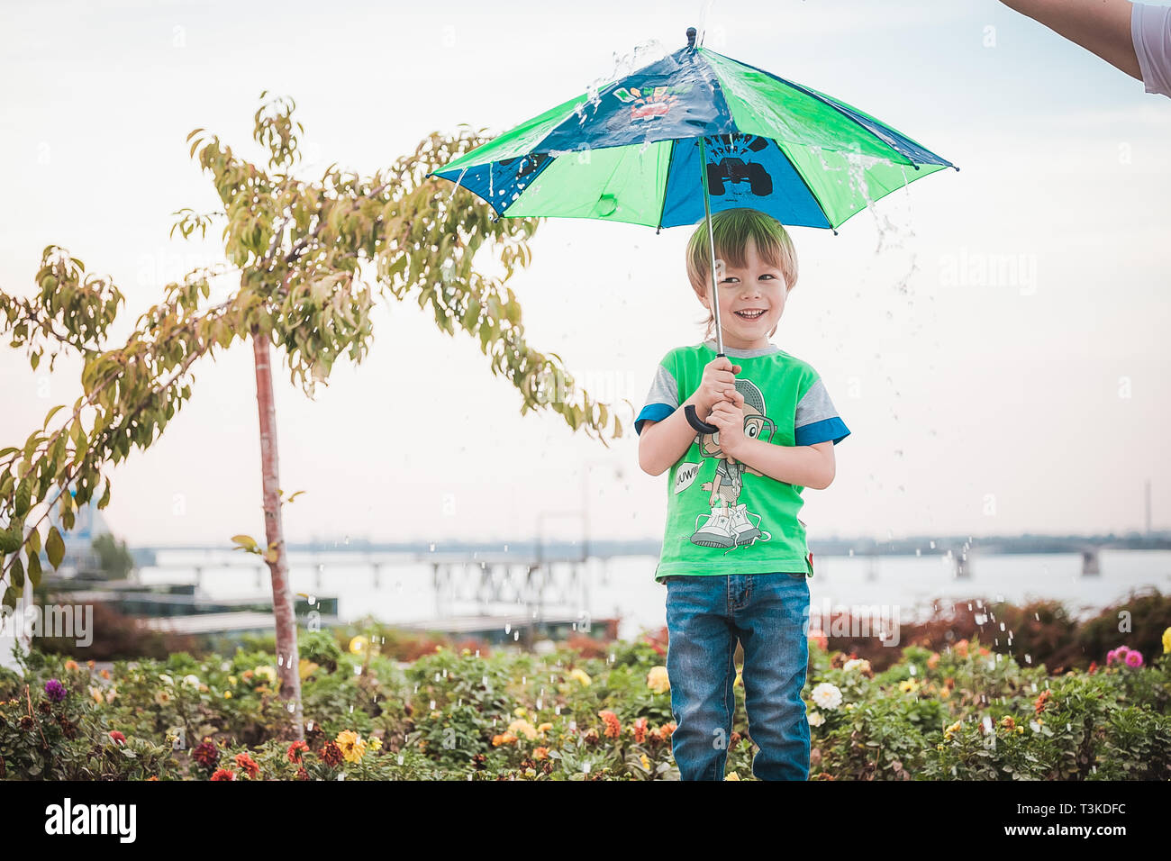 Smiling boy holding an umbrella under rain and sunshine Stock Photo - Alamy
