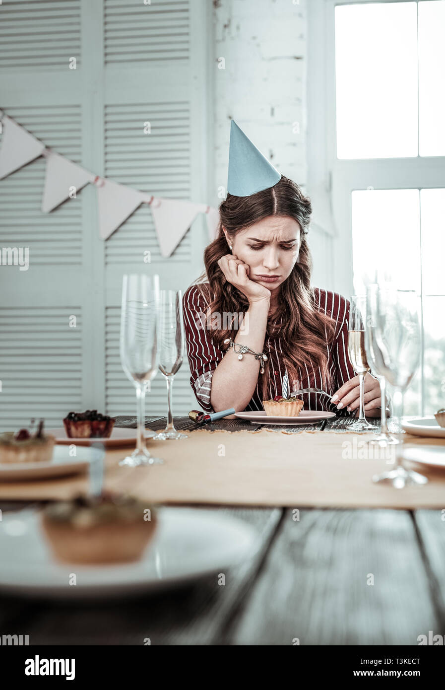 Upset woman eating her birthday cake alone Stock Photo - Alamy