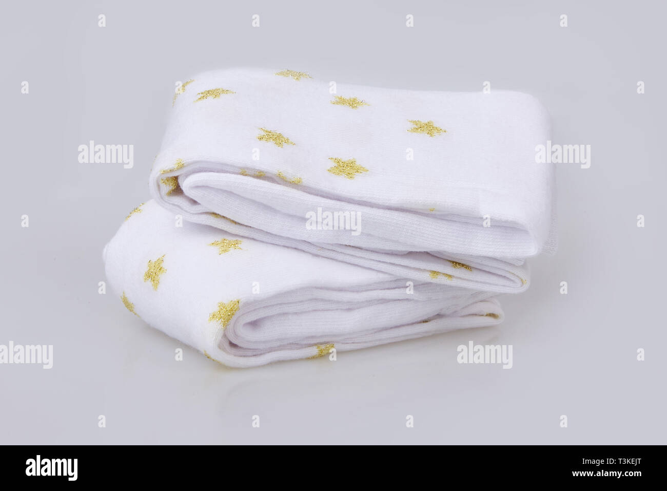 Two pairs of white folded child's tights decorated with golden stars ...