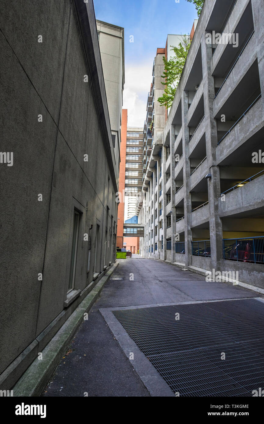A deserted lane way with a parking garage on the right side. Garbage ...