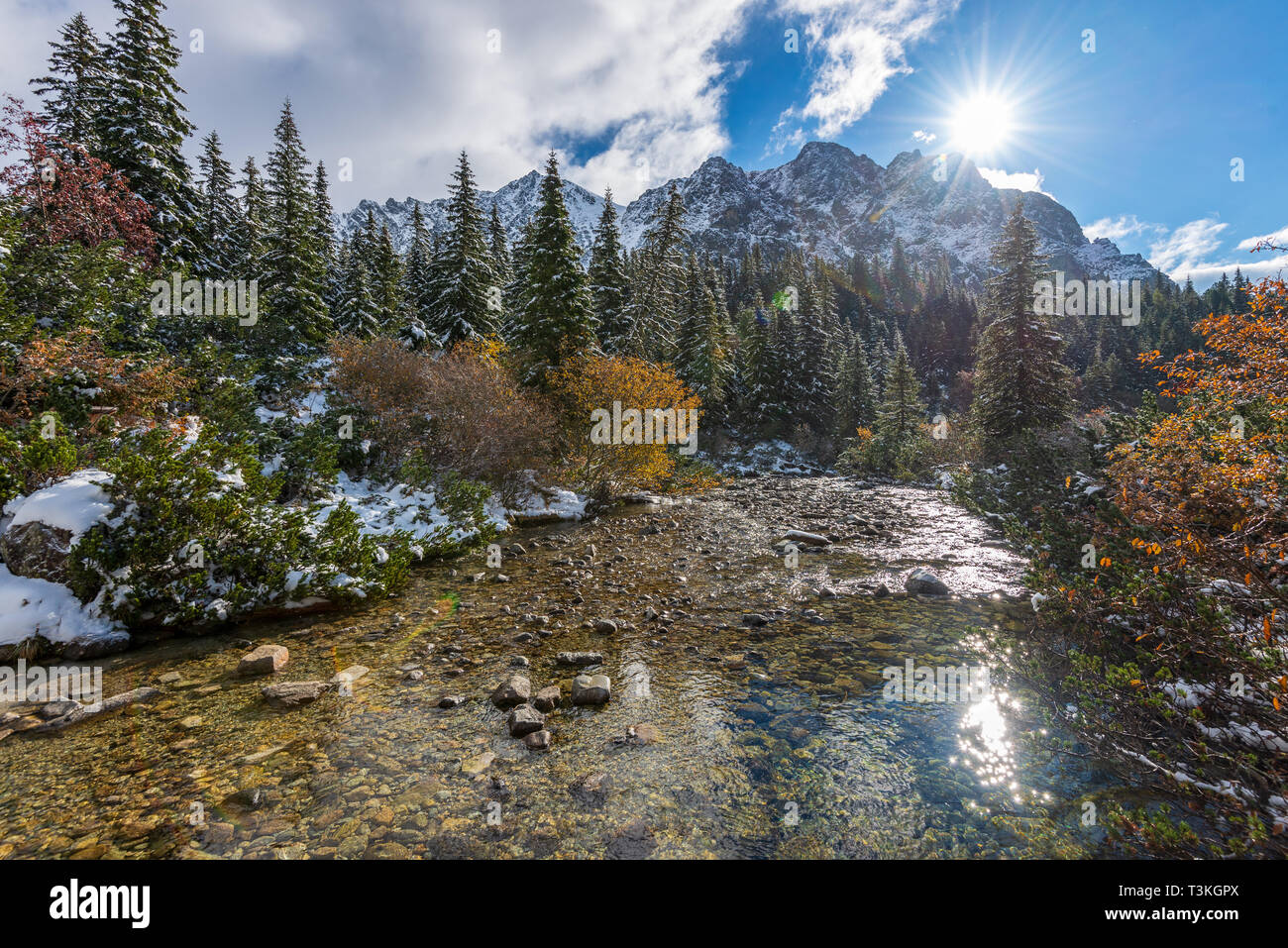mountain lake in winter with calm open water and mountain wall behind ...