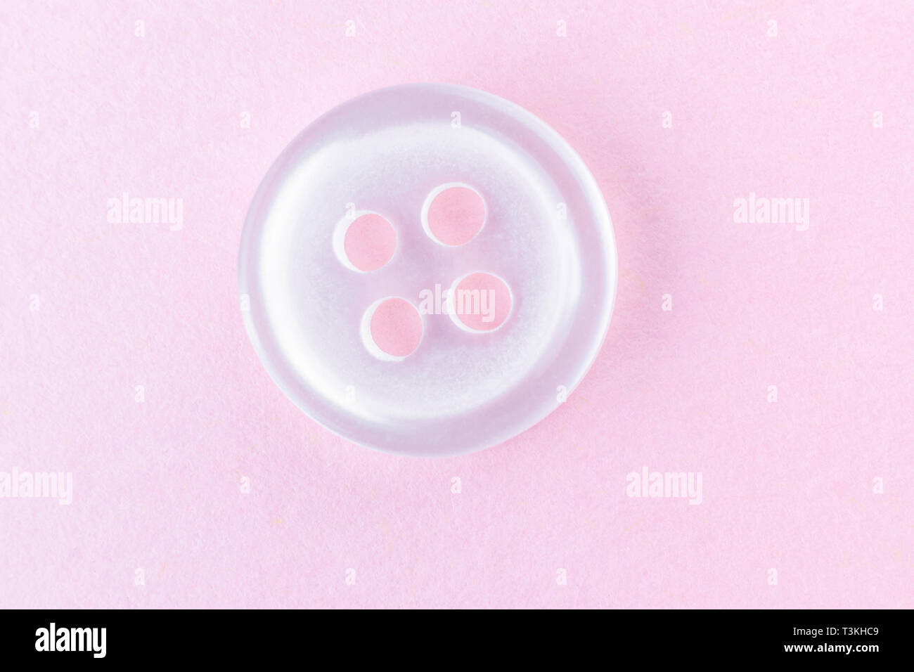 White button closeup on a pastel pink background. Bright image suitable ...
