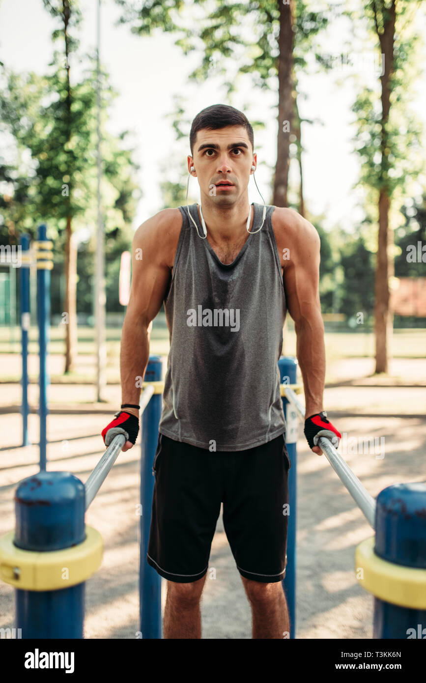 Man doing exercise on parallel bars, front view Stock Photo - Alamy
