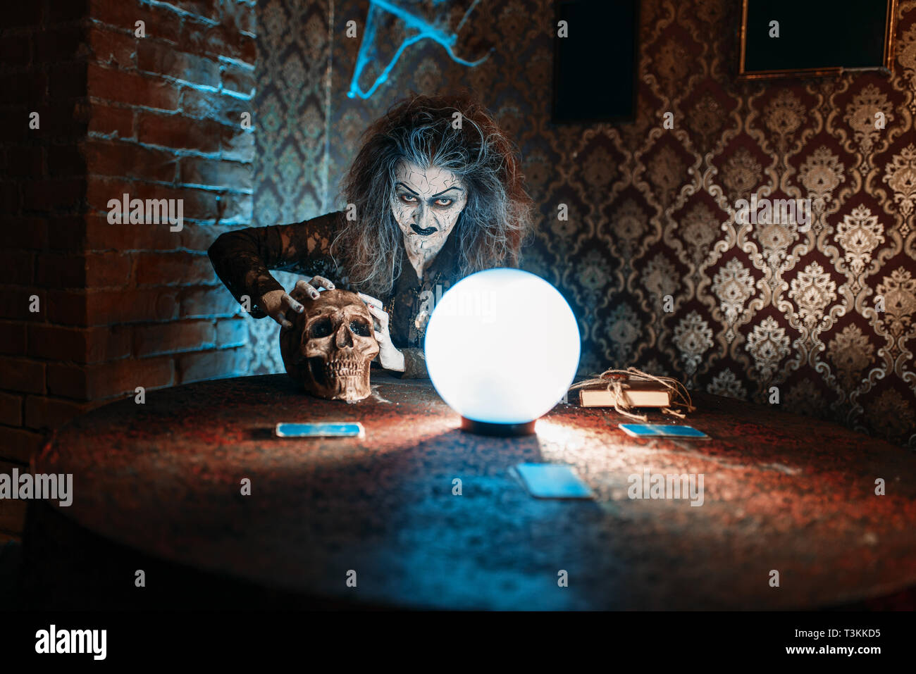 Scary witch with human skull over a crystal ball Stock Photo - Alamy