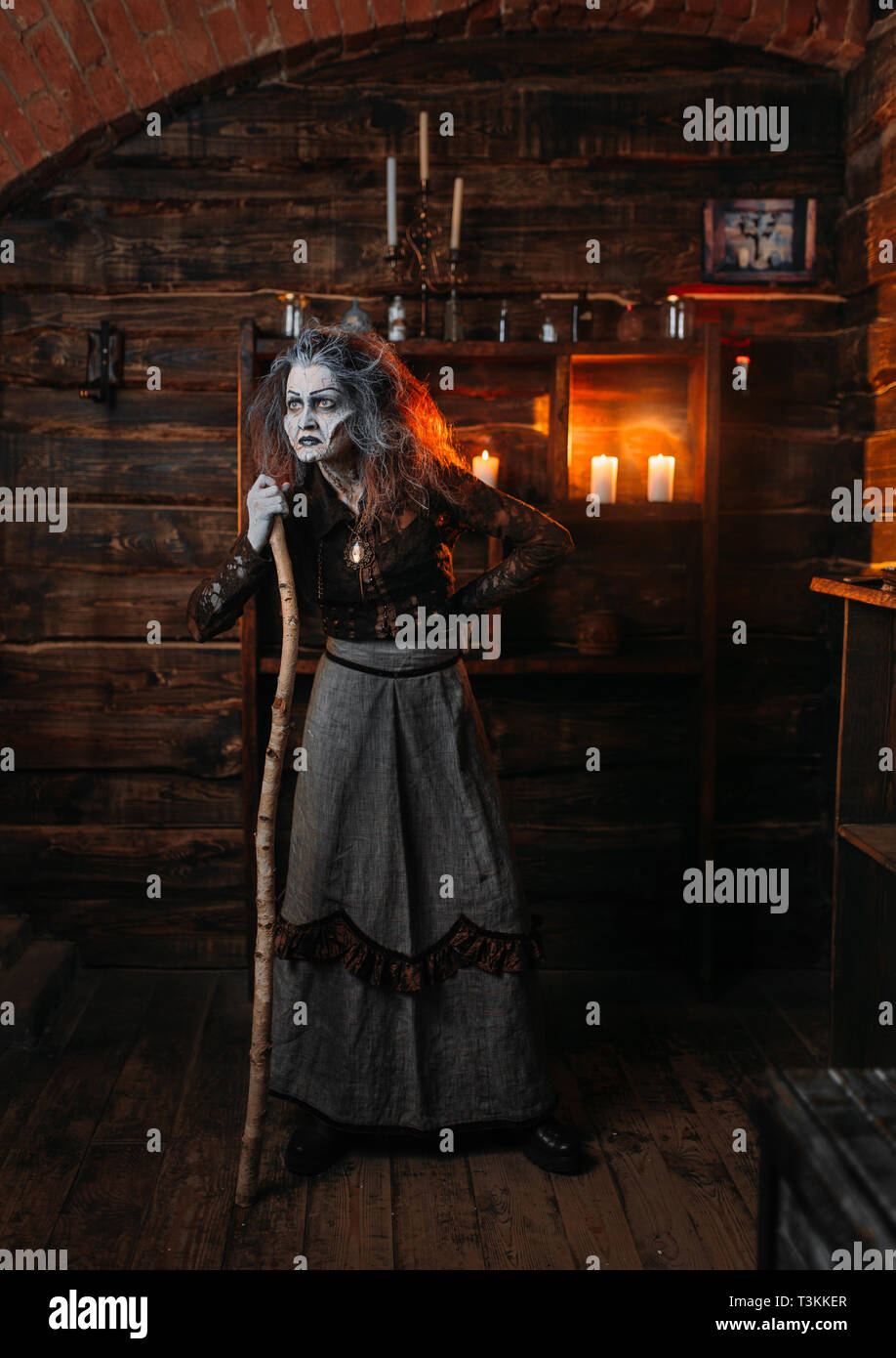 Scary witch stands leaning on a cane, seance Stock Photo - Alamy