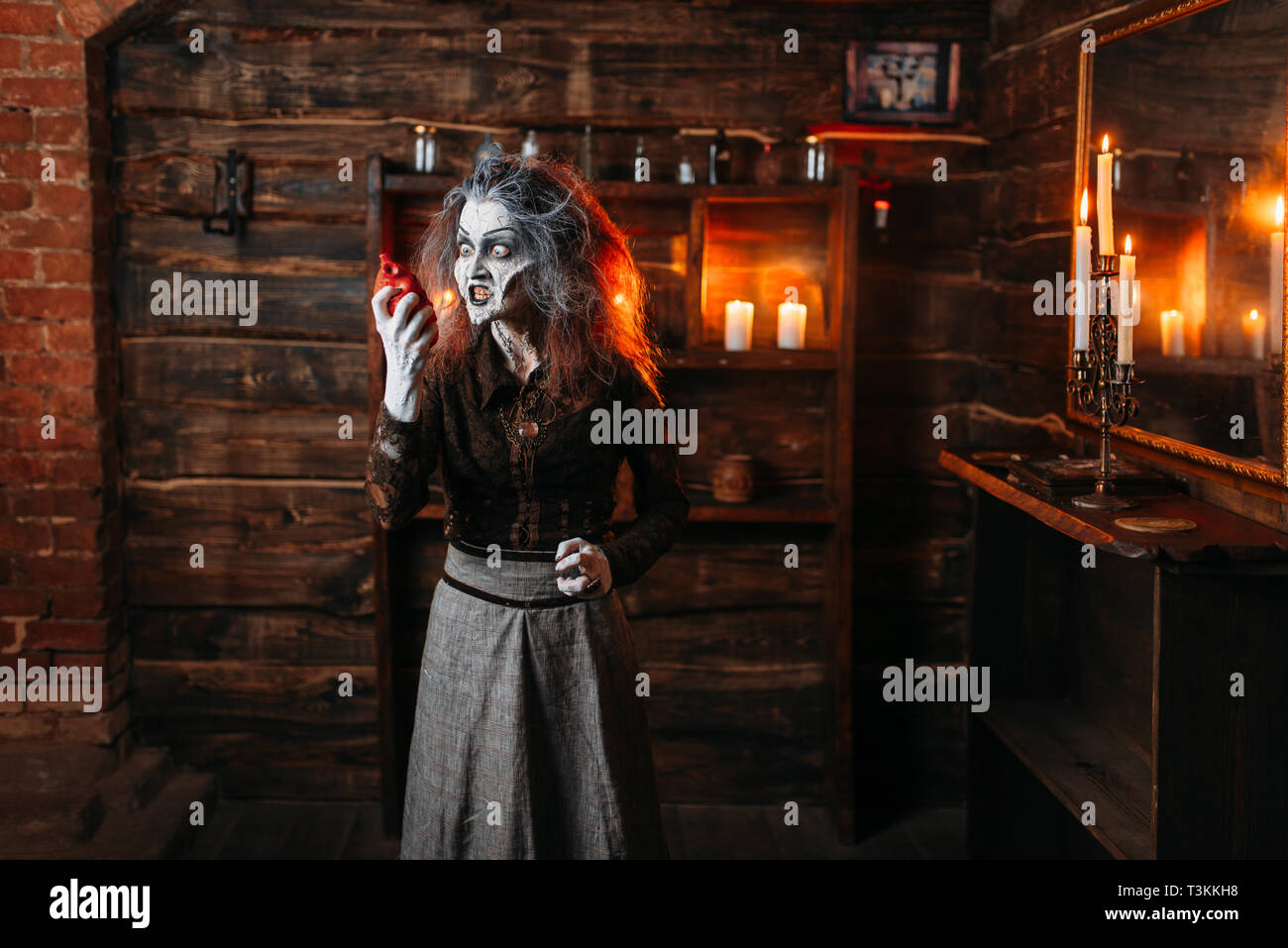 Scary witch holds human heart at the mirror Stock Photo - Alamy