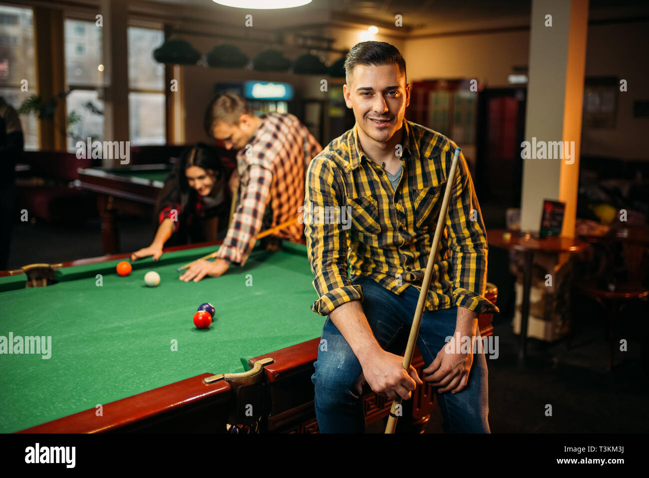 Two male billiard players with cues poses Stock Photo - Alamy