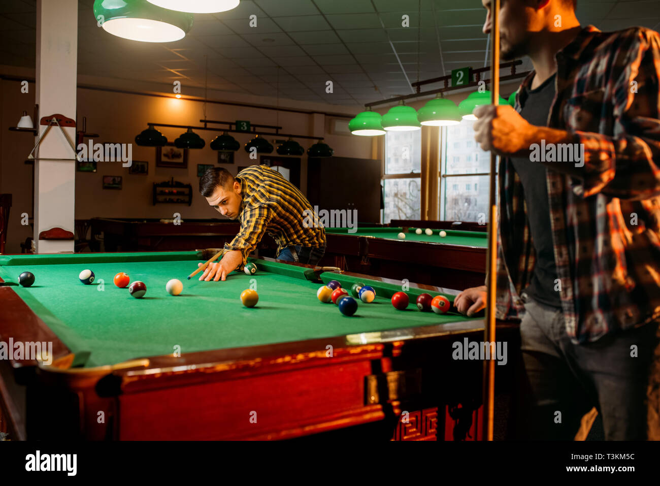 Two male billiard players with cues poses Stock Photo - Alamy