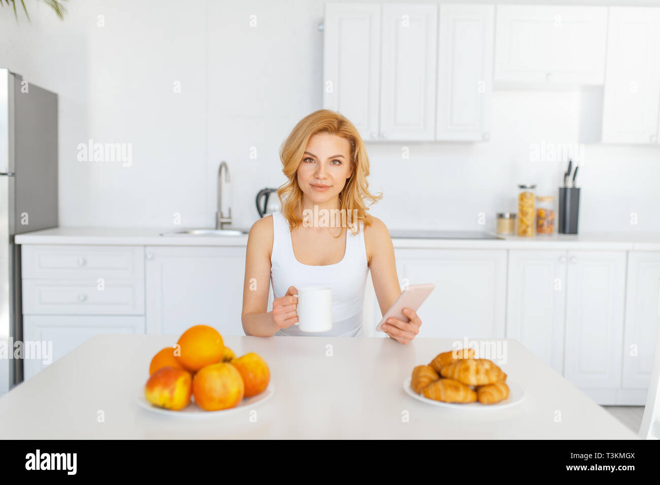 Happy woman at the table with fruits and baking Stock Photo - Alamy