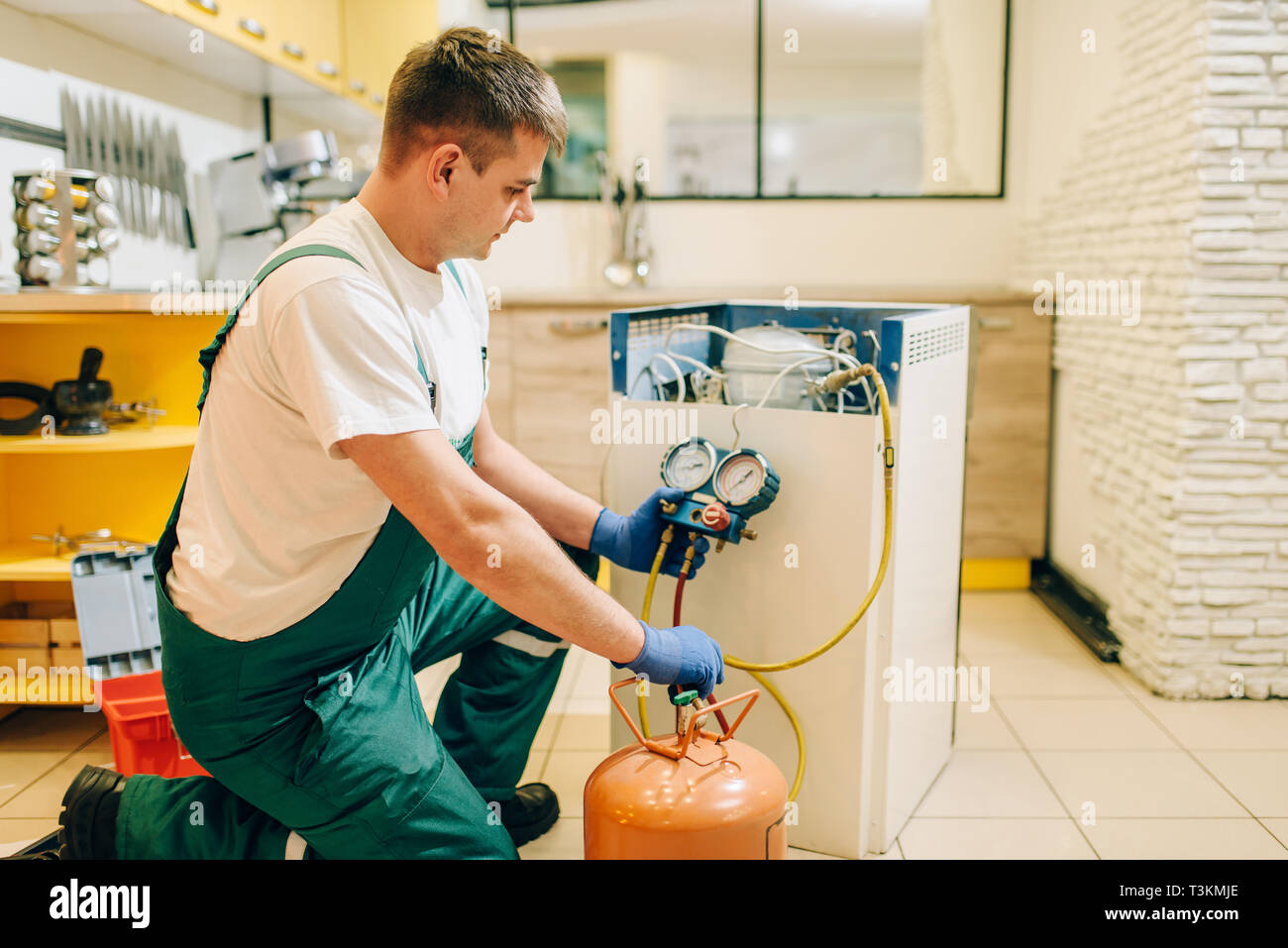Worker in uniform fills compressor of refrigerator Stock Photo - Alamy