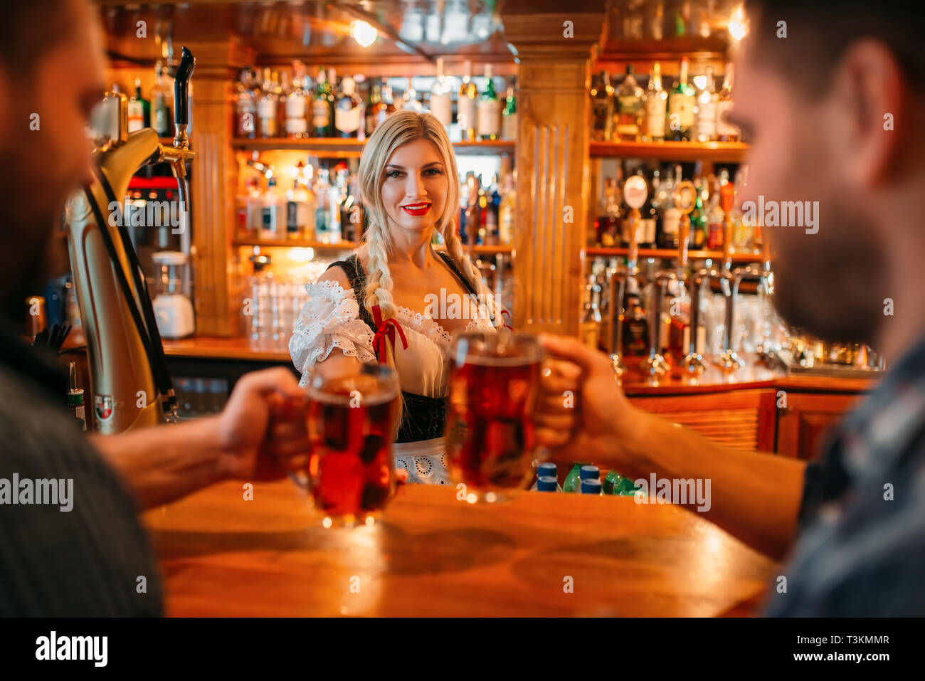 Two male friends clinking mugs with beer in pub Stock Photo - Alamy
