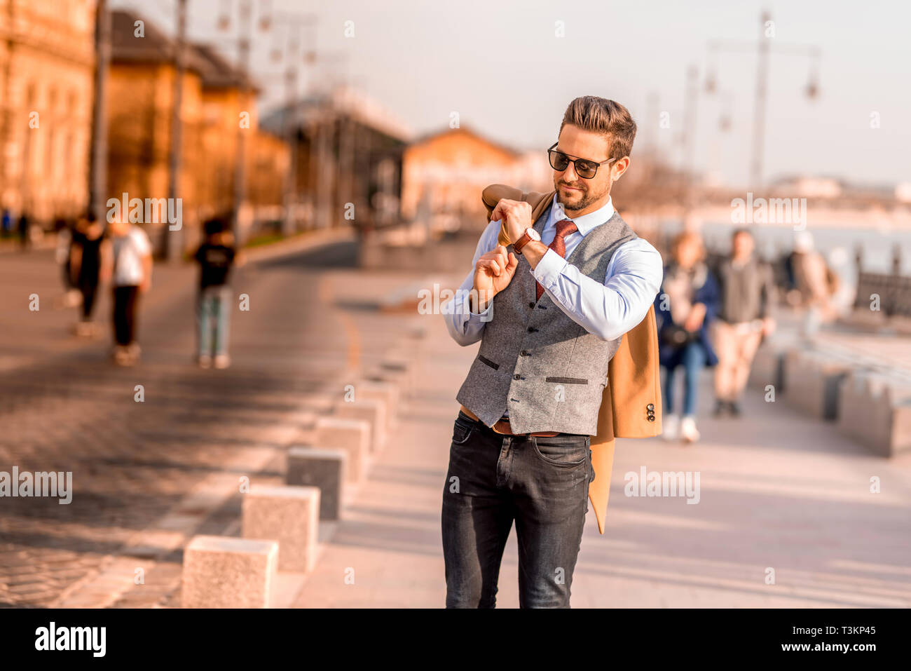 A handsome elegant man walking on the streets and checking the time on ...