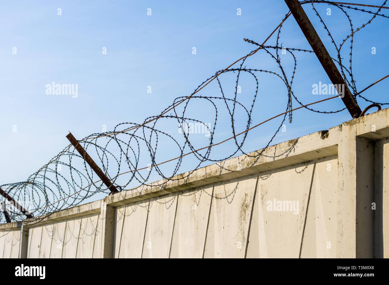 Concrete wall with razor barbed tape wire on blue sky background Stock ...