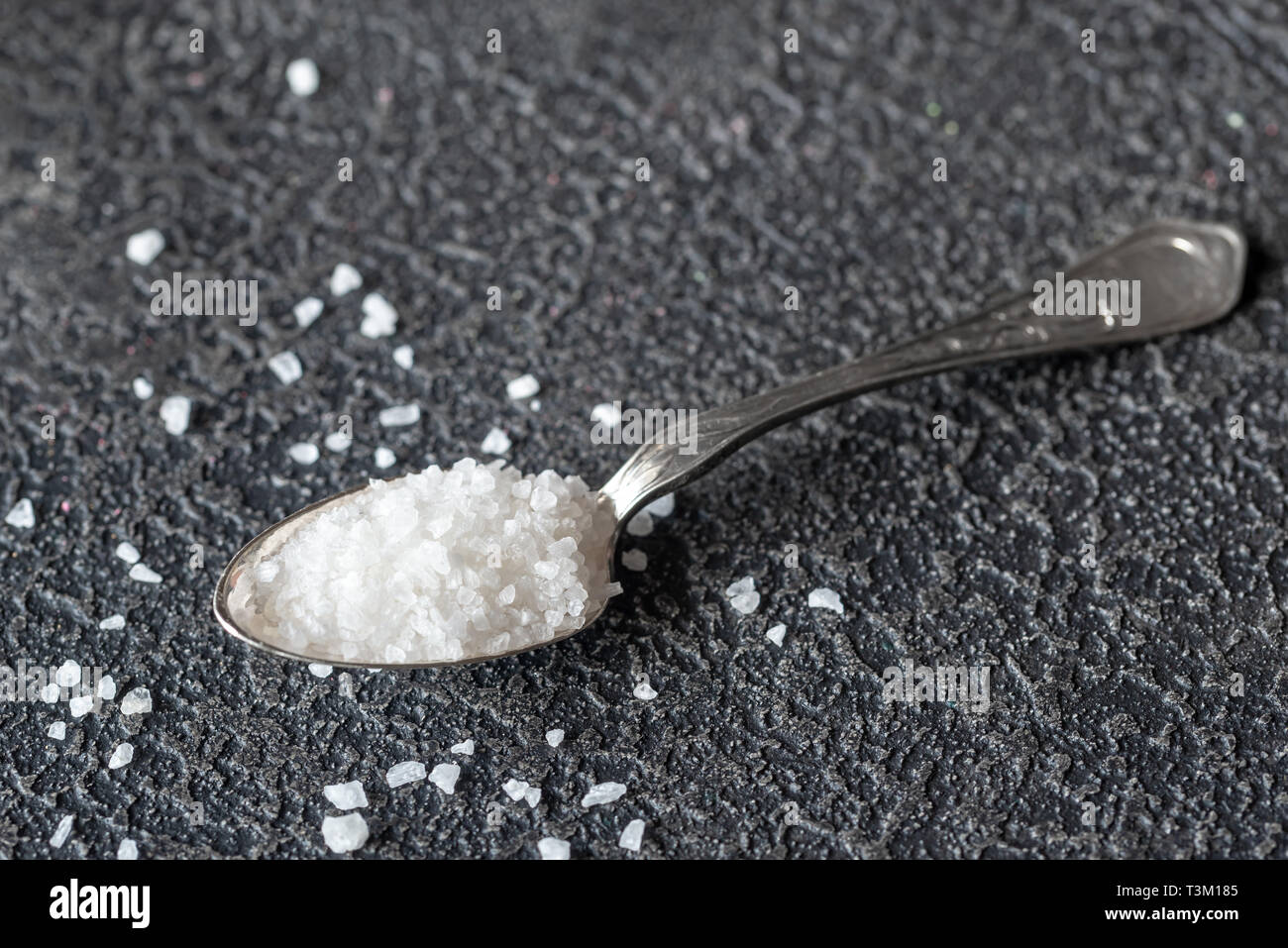 Silver spoon of sea salt on the dark background Stock Photo - Alamy