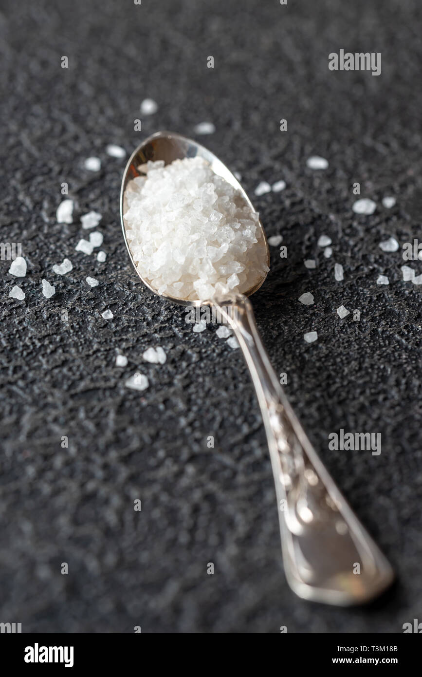 Silver spoon of sea salt on the dark background Stock Photo - Alamy
