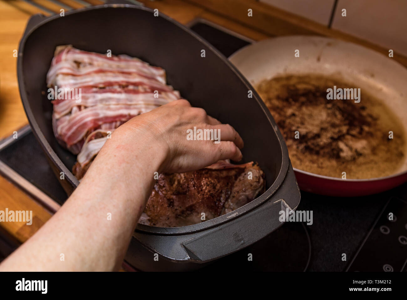 A woman's hand is filling a roast with bacon Stock Photo - Alamy