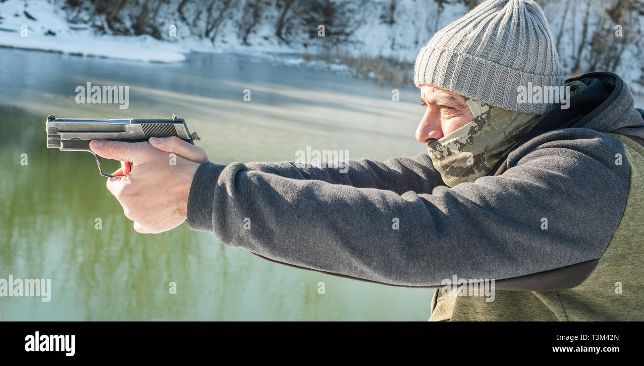 Detail view of shooter holding gun in hand and shooting on the winter ...