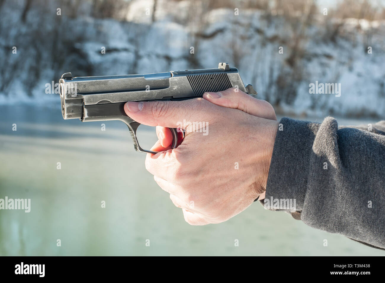 Detail view of shooter holding gun in hand and shooting on the winter ...