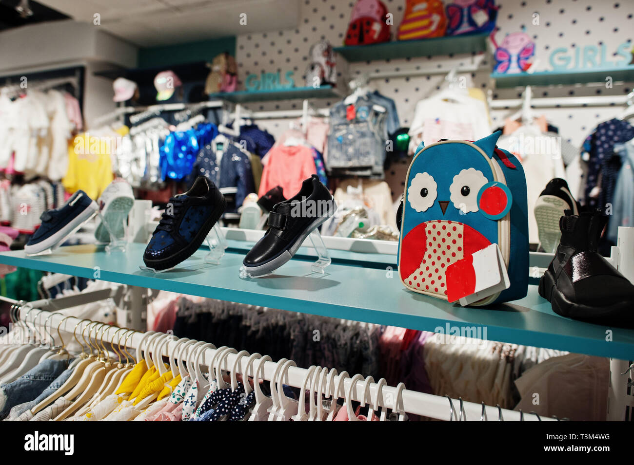 Children's bright clothes hang on the display in the baby clothing ...